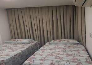 Quarto com duas camas, cada uma com roupa de cama florida e almofadas combinando.