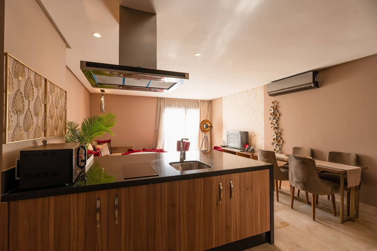 Cozinha moderna com ilha central, armários de madeira e área de jantar com cadeiras.