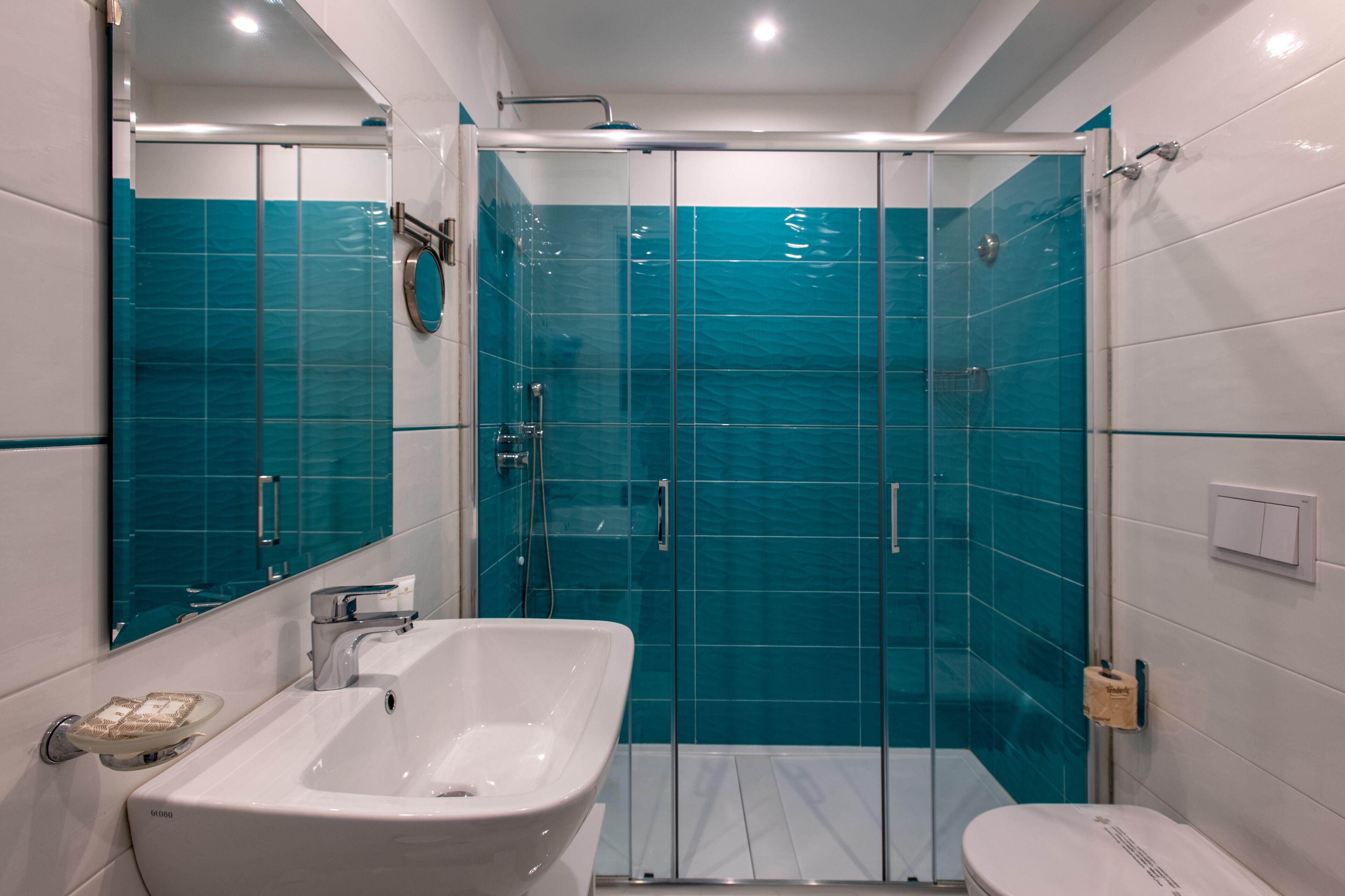Uma casa de banho moderna com cabine de duche em vidro, uma sanita e uma pia branca.