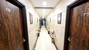 Corredor com portas de madeira numeradas 303 e 305, que dá para um quarto.