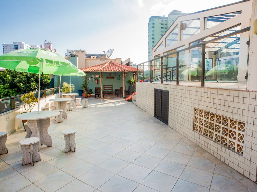 Terraço no telhado com área de estar externa e um guarda-sol verde.