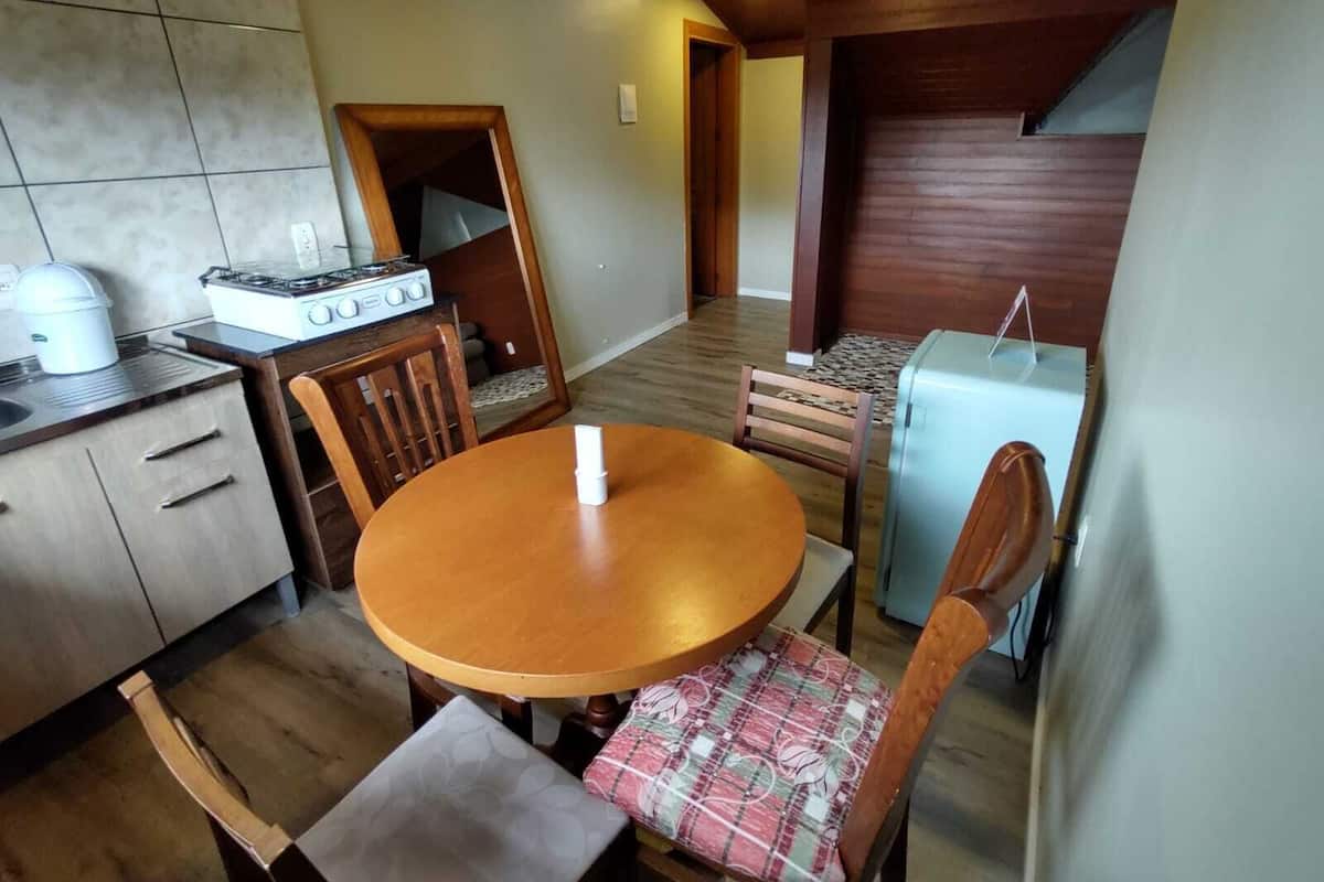 Cozinha compacta com mesa de jantar, cadeiras, fogão e geladeira.