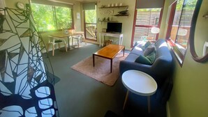 Sala de estar com sofá, mesa de centro, TV e escada com design geométrico.