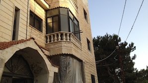 Um edifício com varanda na esquina, janelas amplas e um arco decorativo.