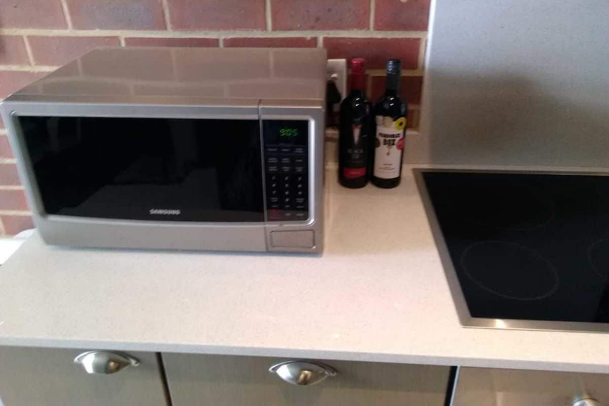Uma cozinha com micro-ondas, duas garrafas de vinho e fogão.