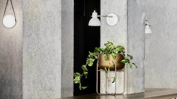 Uma área de bar moderna com uma longa mesa de madeira, banquetas roxas, uma luminária pendente e uma planta em vaso na parede.