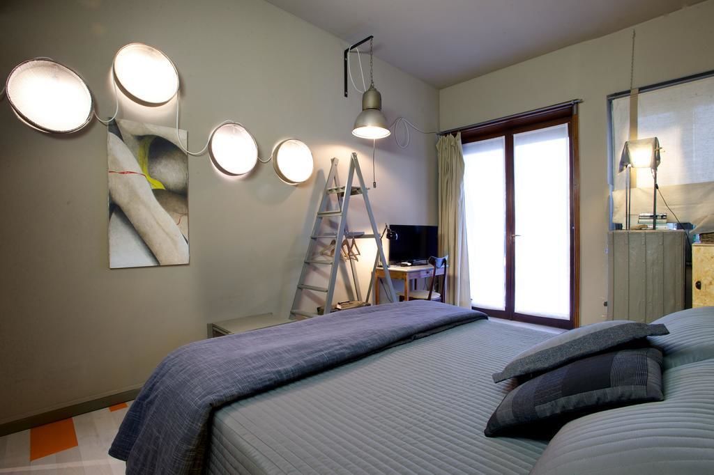 Quarto com cama, escrivaninha, escada e uma janela grande.