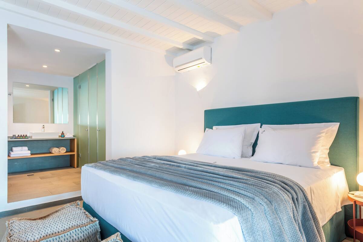 Quarto moderno com uma cama, mesa de cabeceira, espelho e guarda-roupa.