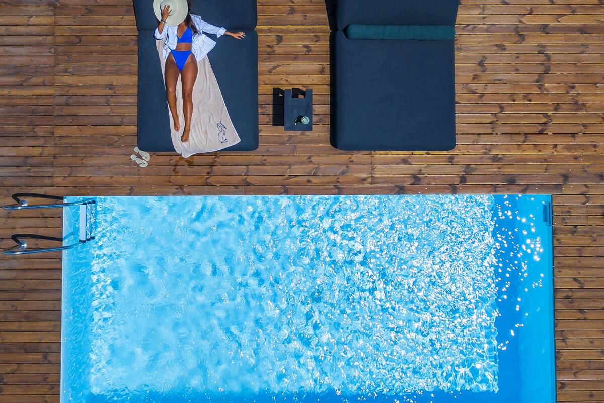 Uma área à beira da piscina com espreguiçadeira, toalha e uma mesa pequena.