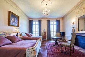 Quarto de hotel com duas camas, um candelabro, um espelho grande e um tapete vermelho.