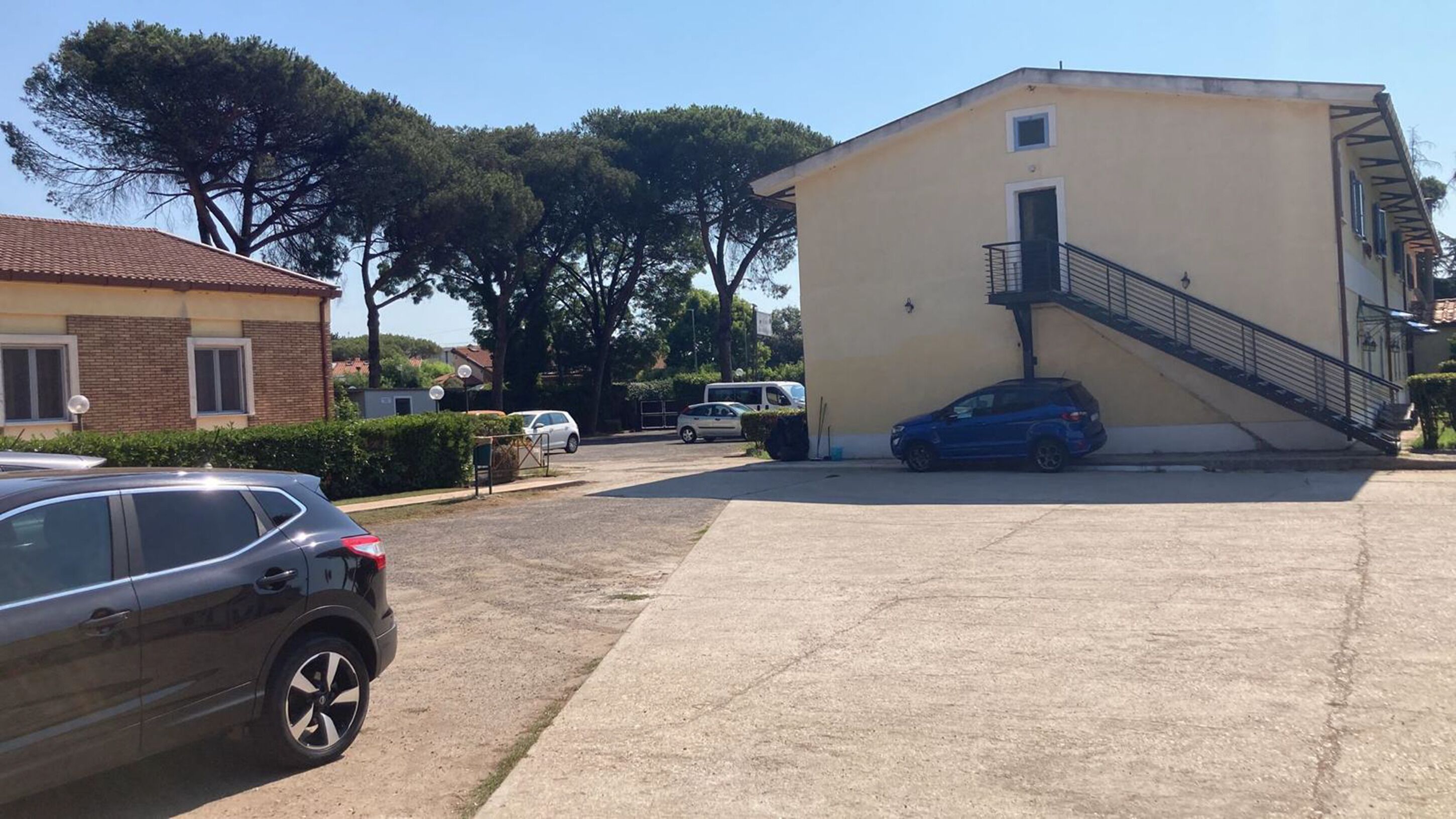 Uma área de estacionamento com um edifício que possui uma escadaria que dá acesso a um segundo andar.