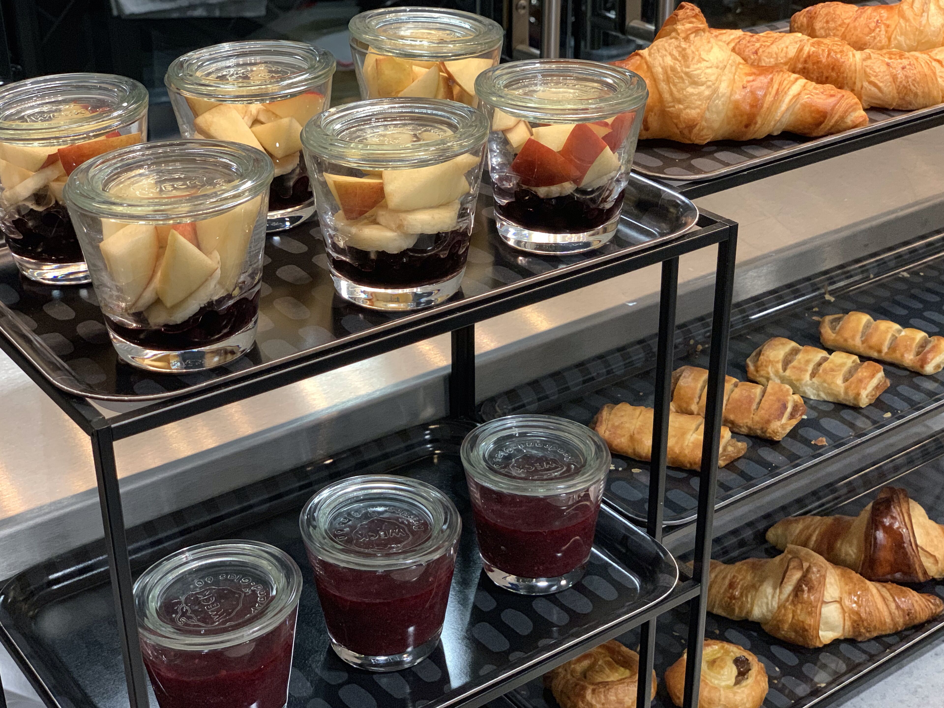 Exposição de alimentos, incluindo potes de geleia de fruta e doces numa estrutura de metal.