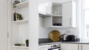 Uma cozinha moderna com armários brancos, bancada preta e piso de madeira.