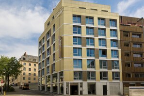 Um hotel com vários andares e design moderno, com uma placa 'Odals' em destaque na fachada.