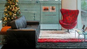 Um hall moderno com um sofá de couro preto, uma poltrona vermelha, um pinheiro de Natal e um candelabro.