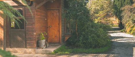 Uma cabana rústica de madeira, com porta de madeira e um pequeno alpendre.