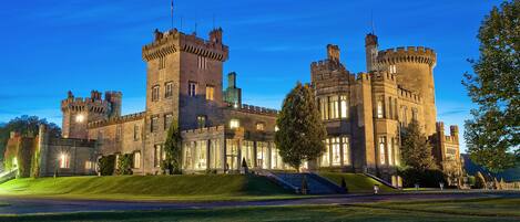 Um castelo grande e histórico, com várias torres e um gramado bem cuidado.