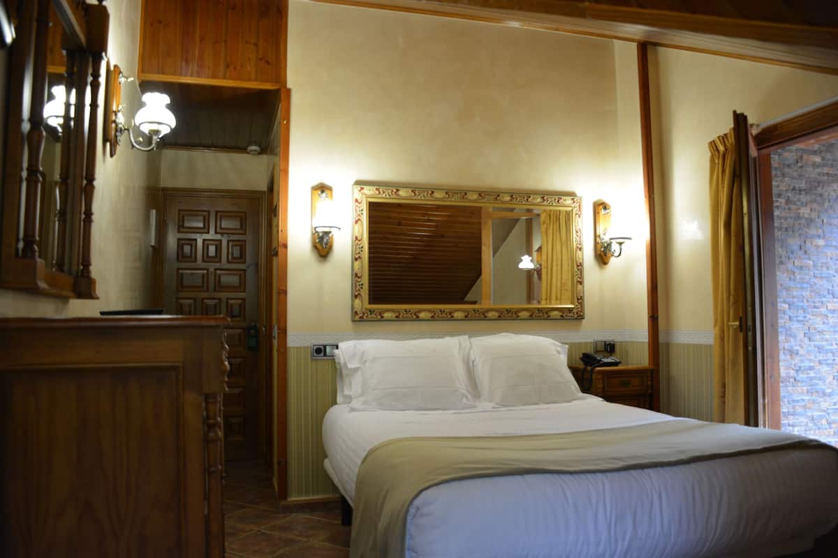Quarto de hotel com cama de madeira, um espelho grande e um guarda-roupa de madeira.