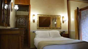 Quarto de hotel com cama de madeira, um espelho grande e um guarda-roupa de madeira.