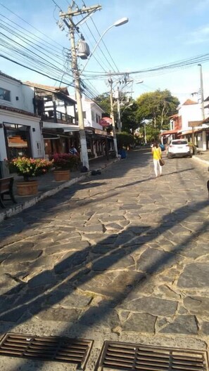 Rua com calçada de pedra, edifícios de ambos os lados e fios elétricos aéreos.