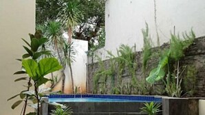 Uma área de piscina com vasos de plantas e uma parede de pedra.
