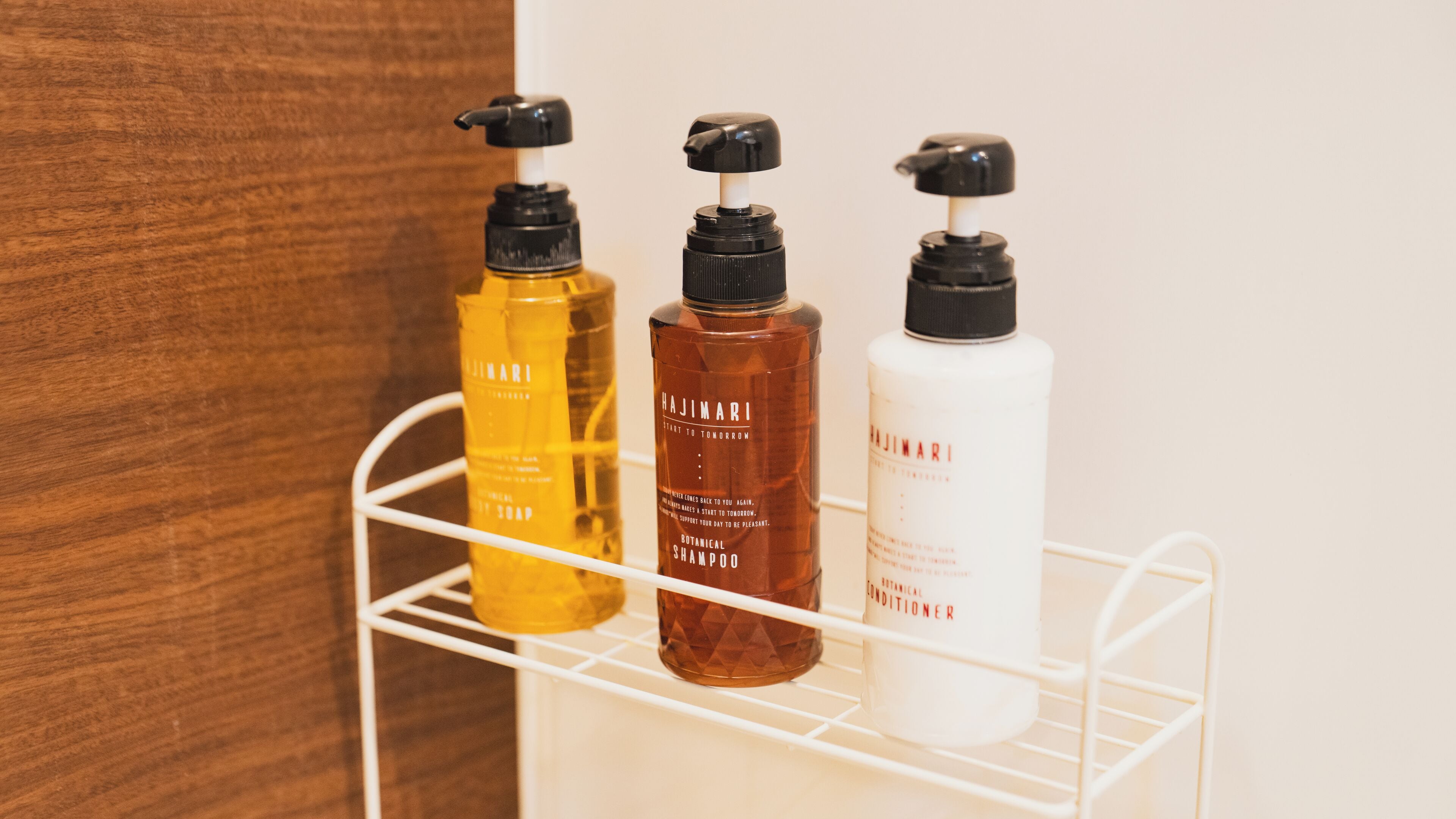 Estante metálica branca com três frascos de produtos Hajimari.
