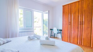 Quarto de hotel com uma cama grande, um guarda-roupa de madeira, uma secretária e vista pela janela.