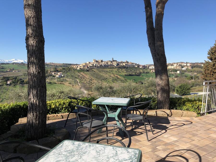 Um pátio com mesa e cadeiras, com vista para uma vila pitoresca com edifícios numa colina.