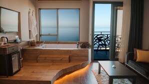 Uma casa de banho moderna com uma toucador de madeira, uma banheira e uma grande janela com vista para o mar.
