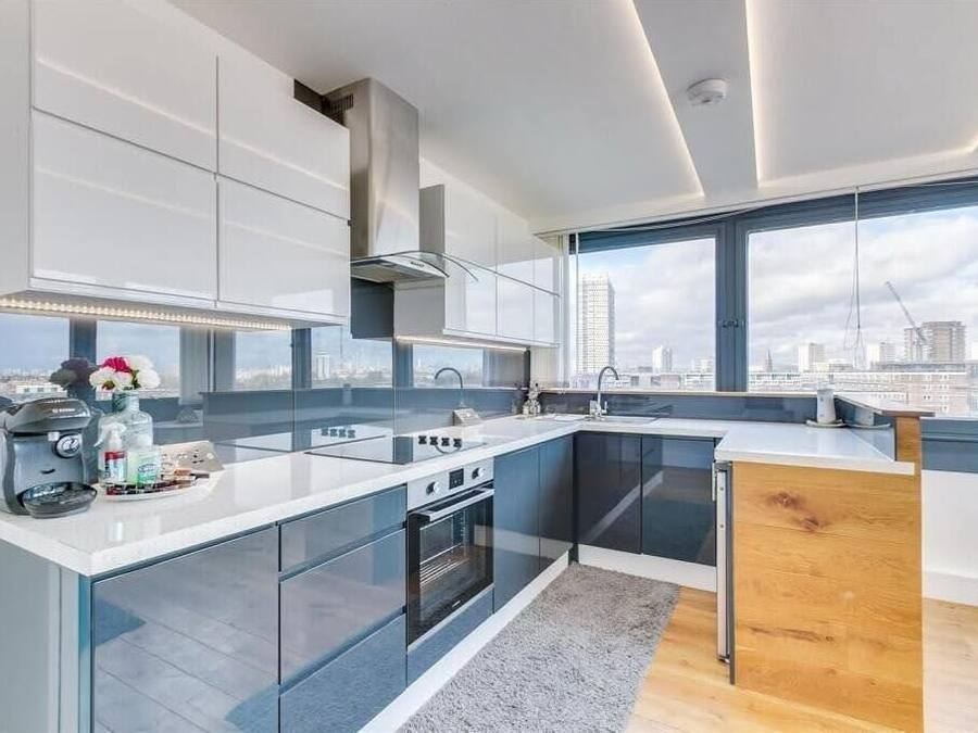 Cozinha moderna com uma ilha grande, eletrodomésticos embutidos e vista para a cidade através de amplas janelas.