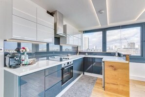 Cozinha moderna com uma ilha grande, eletrodomésticos embutidos e vista para a cidade através de amplas janelas.