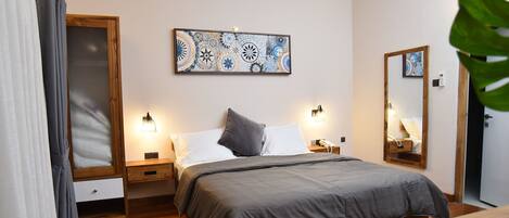 Quarto com cama, mesas de cabeceira, espelho e uma obra de arte na parede.