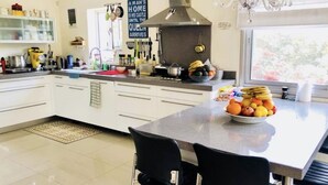 Cozinha moderna com armários brancos, ilha central e lustre.