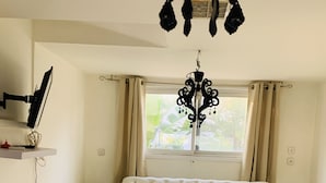 Quarto com uma cama grande, uma escrivaninha, uma cadeira, um guarda-roupa e um candelabro.