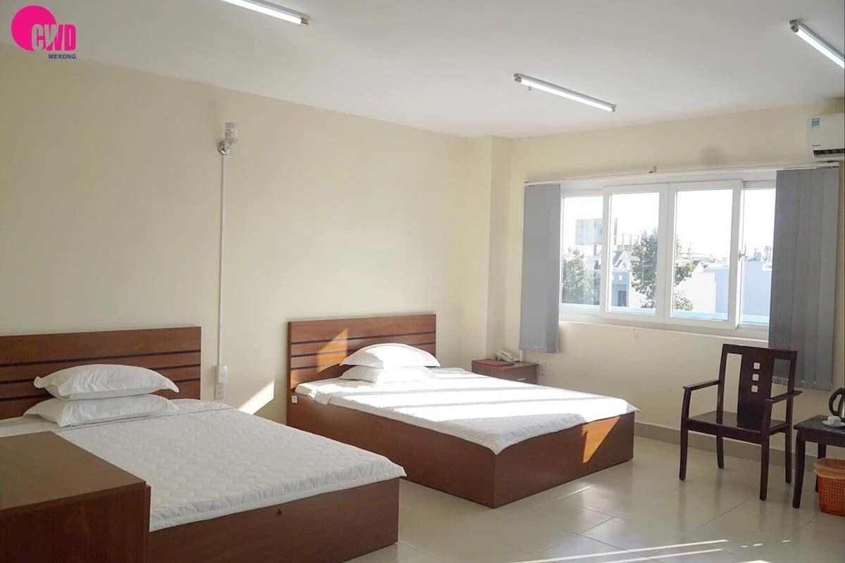 Quarto de hotel com duas camas, uma mesa e uma cadeira.