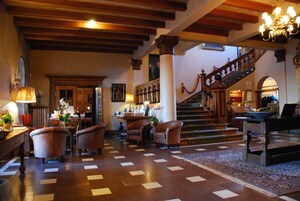 Um hall amplo com uma escadaria imponente, piso de madeira e decoração clássica.