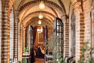 Um corredor com arcos de tijolo, luminárias pendentes e uma planta.