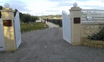 Uma entrada com portão e um caminho de cascalho.