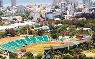 Um estádio com teto curvo, cercado por áreas verdes e edifícios urbanos.