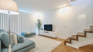 Uma sala de estar moderna com um sofá, uma televisão e uma escada.