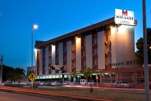 Um hotel com vários andares, uma placa chamativa e uma placa de faixa de pedestres.