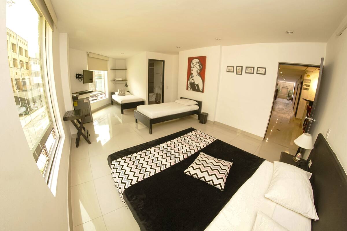 Quarto de hotel moderno com uma cama grande, uma escrivaninha e vista para a cidade.