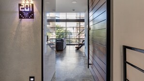 Um corredor moderno com um display digital, uma escada e vista para uma área externa com assentos.