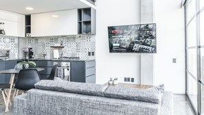 Um interior moderno com cozinha, área de refeições e um amplo sofá cinzento.
