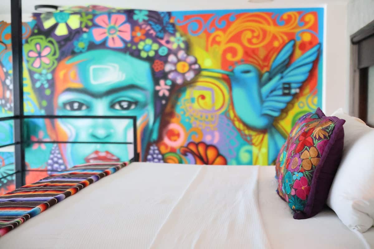 Uma cama com uma tapeçaria colorida e um travesseiro branco.