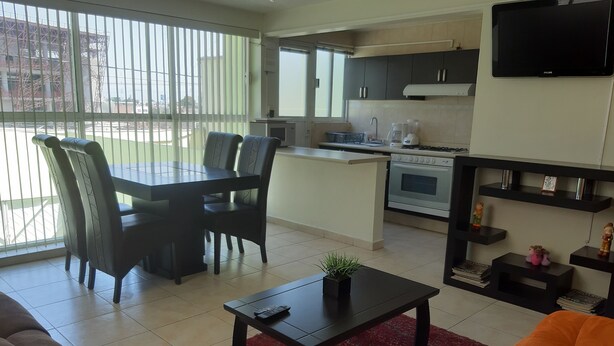 Uma sala de estar moderna com área de jantar, cozinha e janelas amplas.