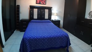 Quarto com cama, mesa de cabeceira, cômoda, guarda-roupa e luminária no teto.