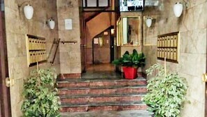 Hall de mármore com vasos vermelhos e escadaria de madeira que leva a um quarto.