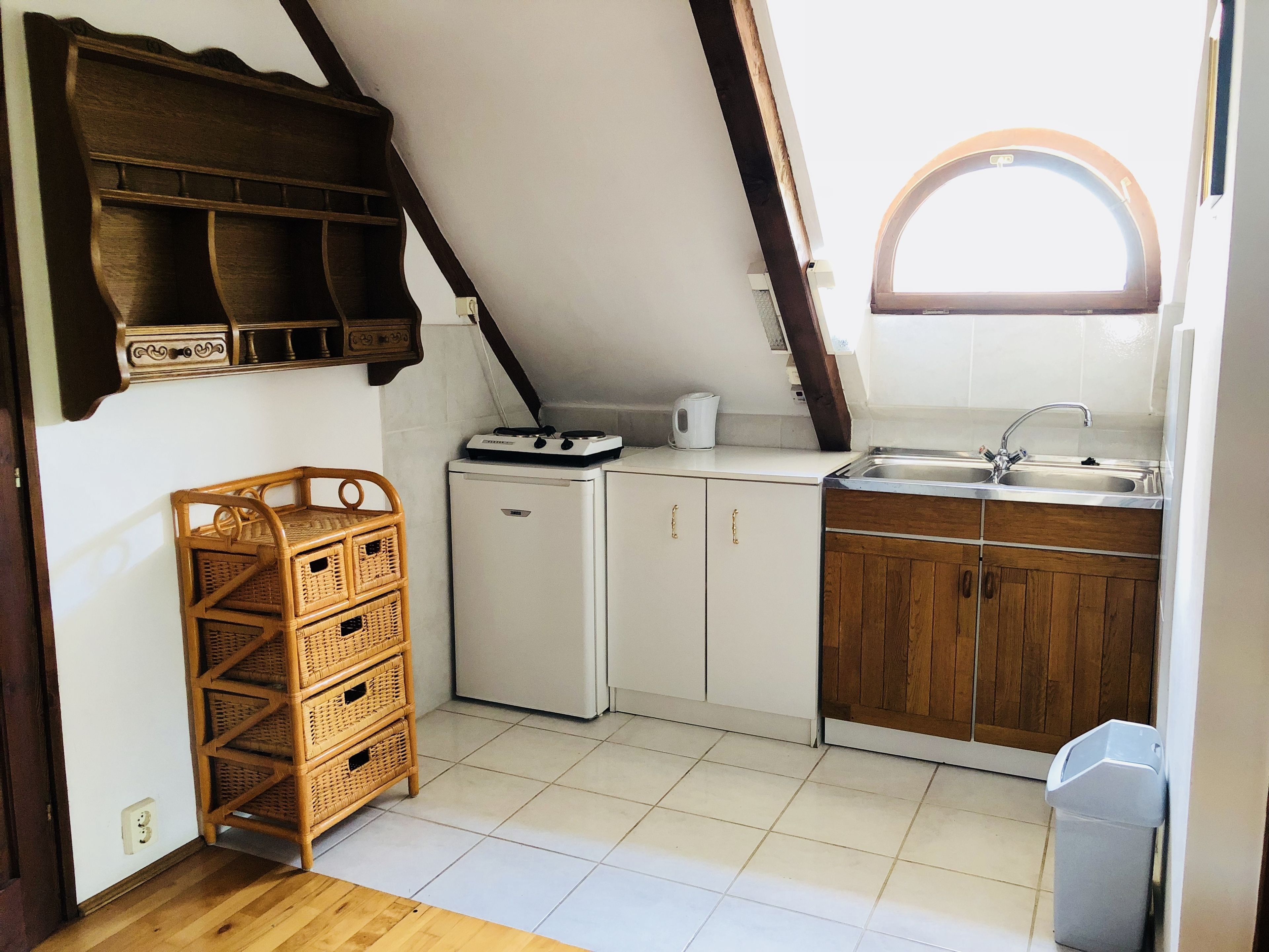 Uma cozinha compacta com armários brancos, bancada de madeira, pia e uma geladeira pequena.