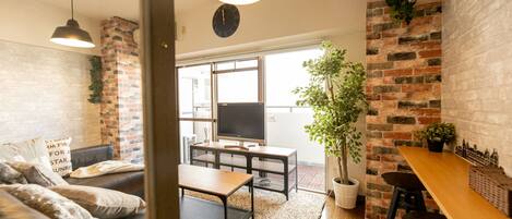 Uma sala de estar moderna com parede de tijolos, um sofá, uma mesa de centro e uma televisão.